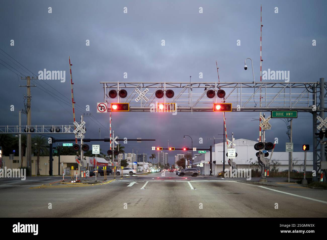 Road intersection with red traffic lights and railway crossing at dusk ...