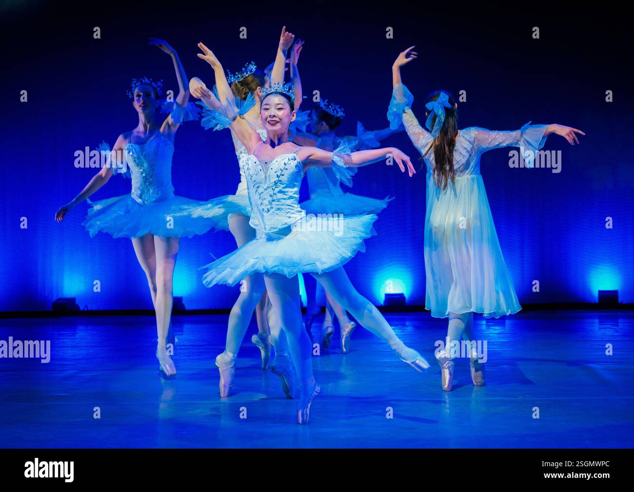 Ballet dancers in white tutus perform gracefully under dramatic stage ...