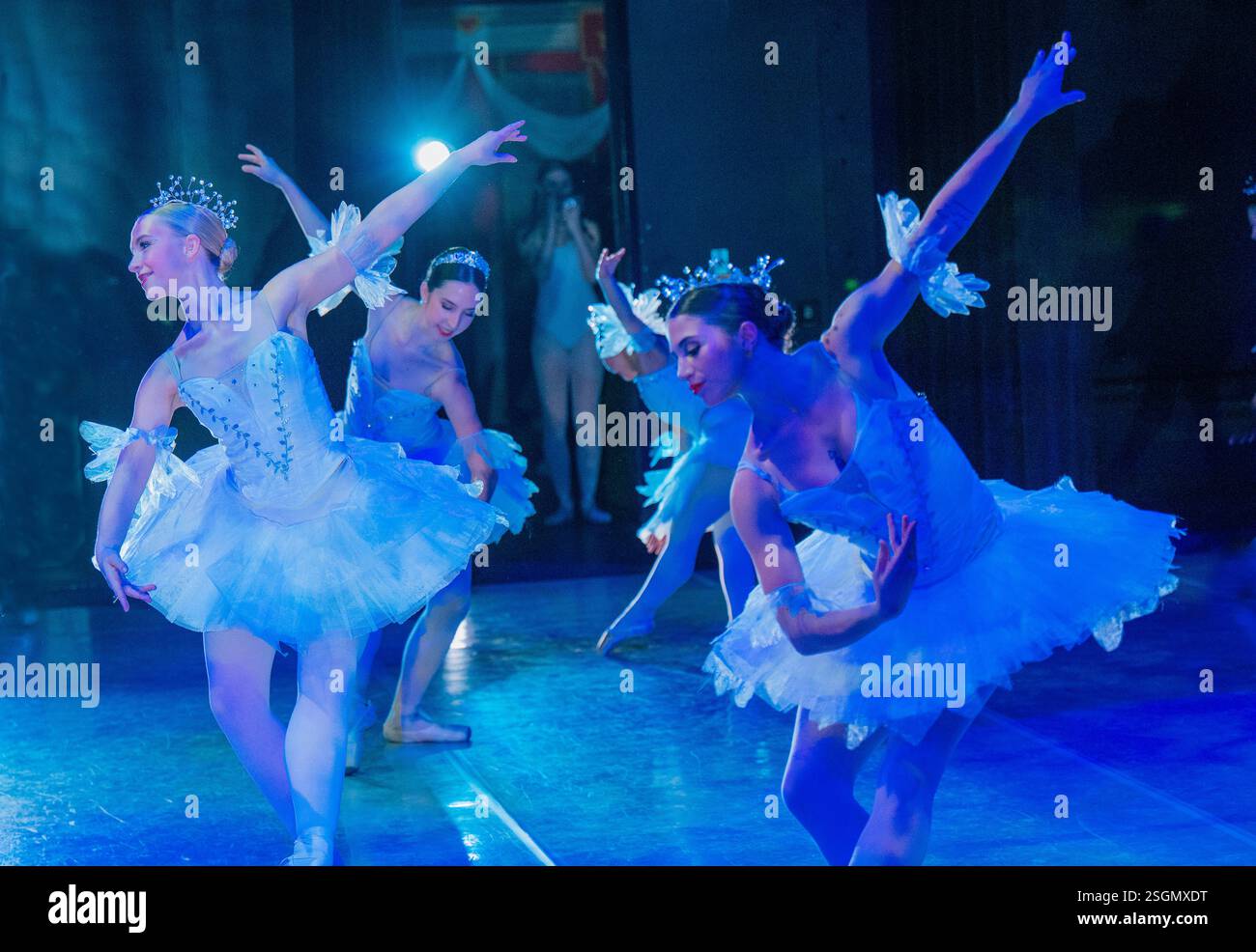 Ballet dancers in elegant blue costumes perform on stage under dramatic ...