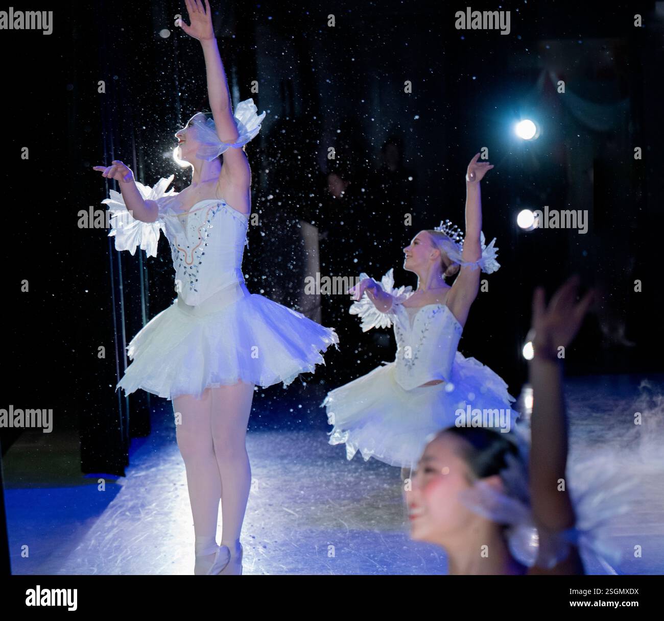 Ballet dancers in white costumes perform gracefully under sparkling ...