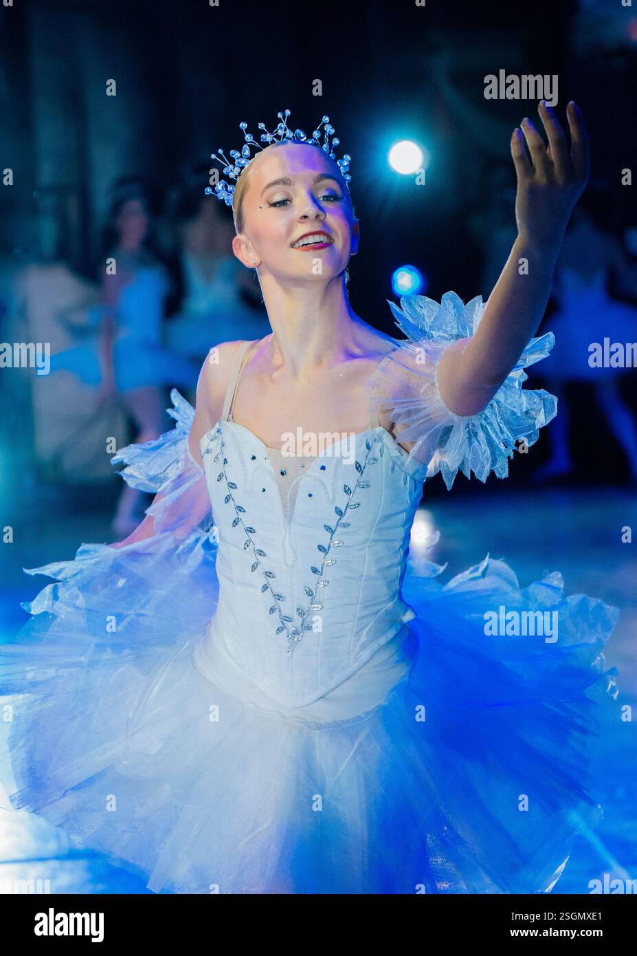 A ballerina in a white tutu and tiara performs a graceful dance under ...