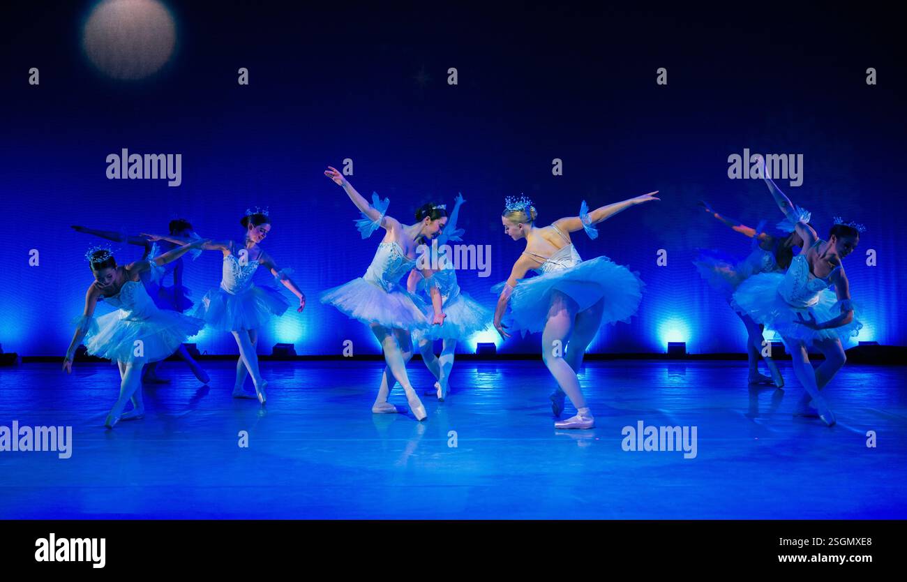 Ballet dancers perform in blue tutus on stage with vibrant lighting ...