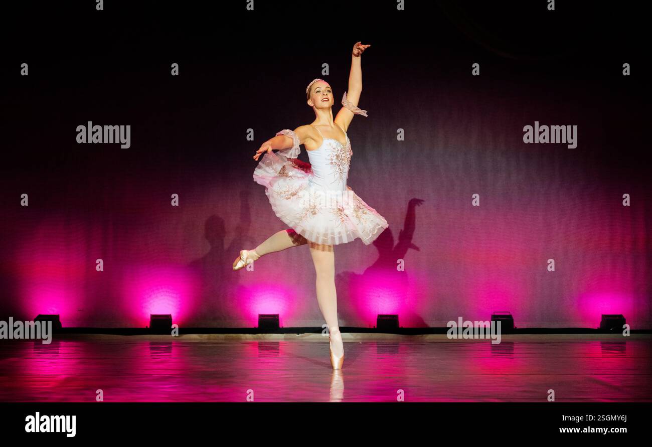 Ballerina gracefully performing on stage in a pink tutu with vibrant ...