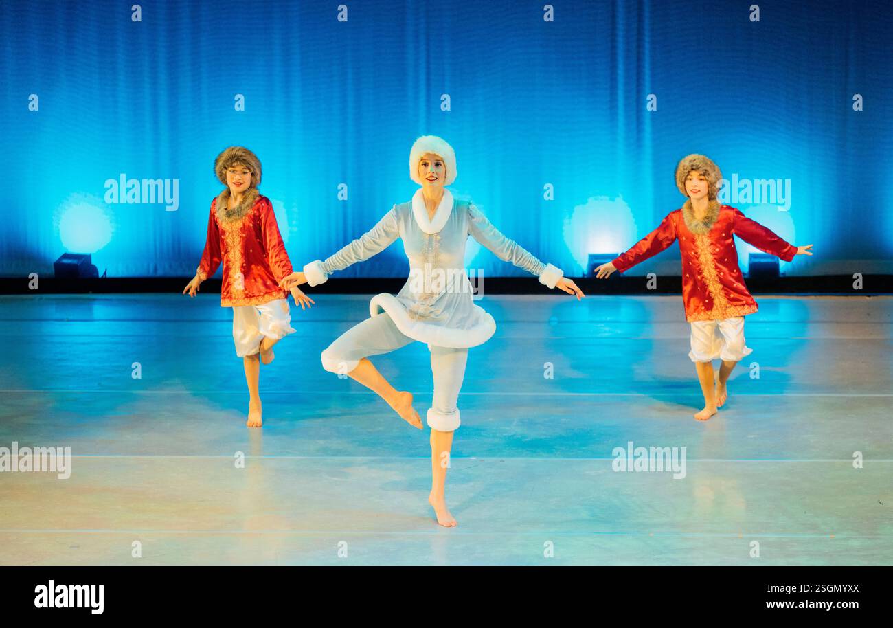 Three ballet dancers in colorful costumes perform on a brightly lit ...