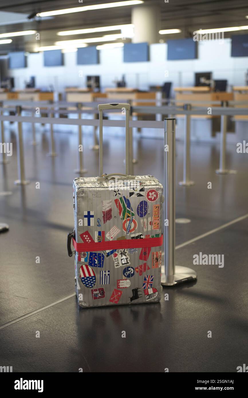 Suitcase covered in colorful travel stickers in an empty airport ...