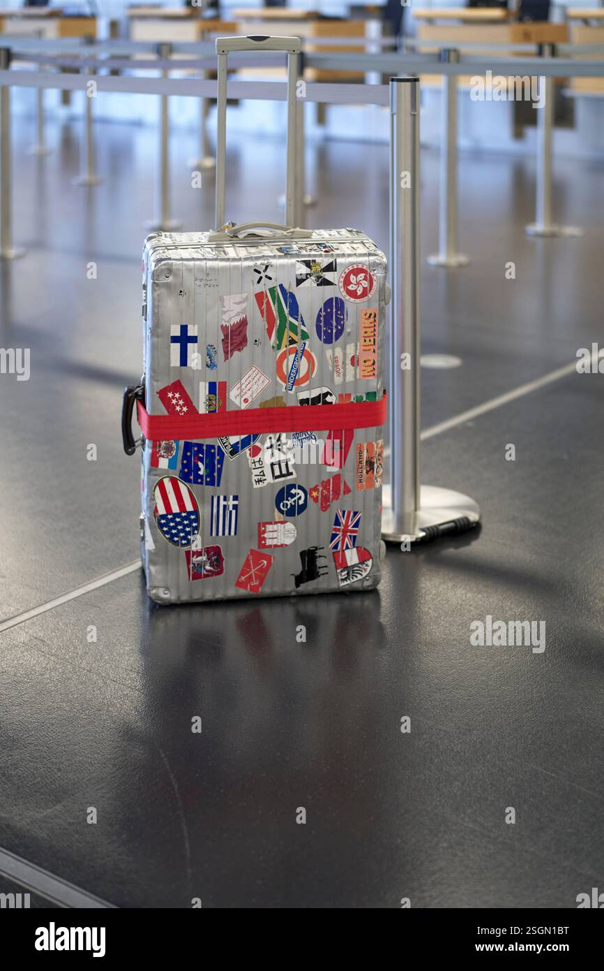 Silver suitcase covered in colorful travel stickers standing in an ...