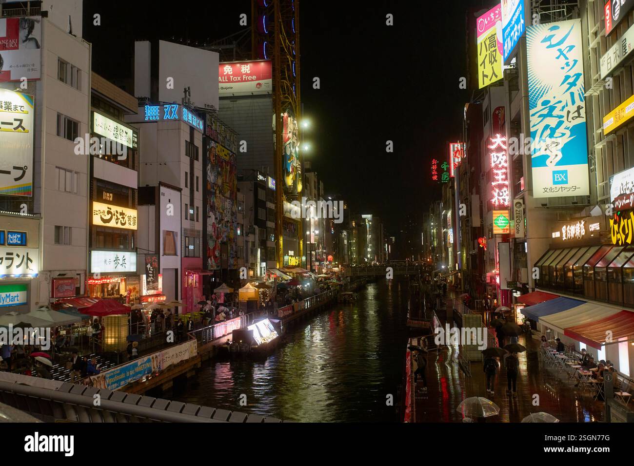 Bustling urban canal scene in Osaka at night with vibrant neon lights ...
