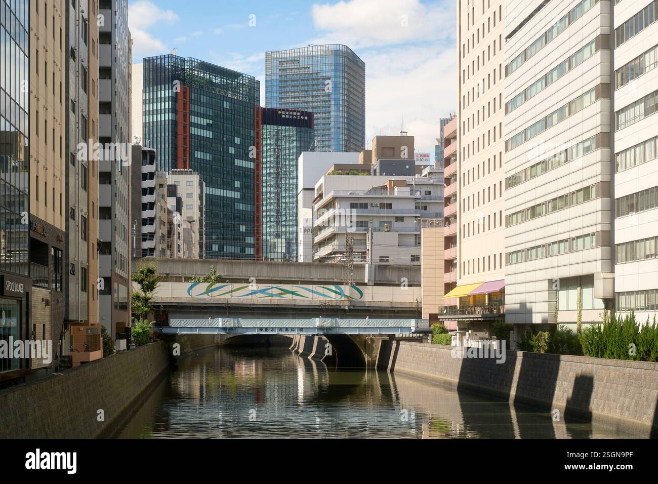 Urban canal surrounded by tall modern buildings under a clear blue sky ...