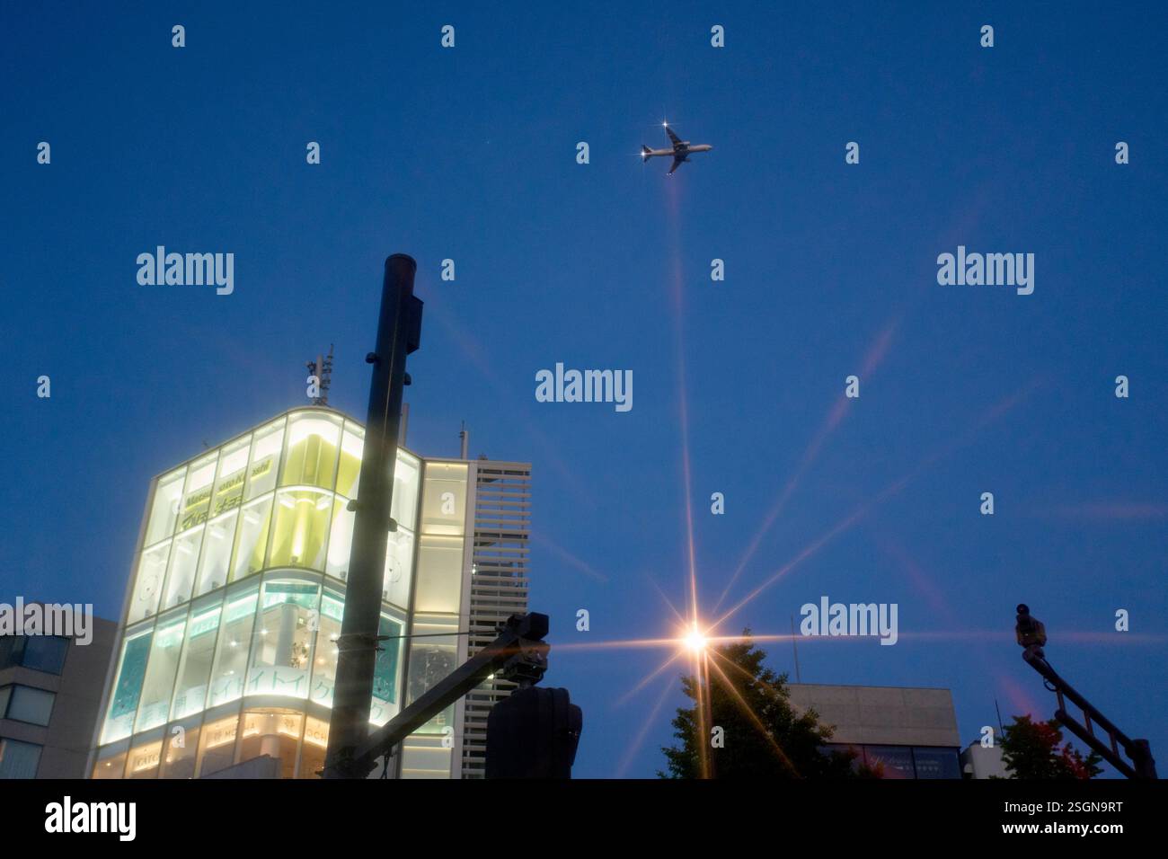 Airplane flying over city buildings with streetlight creating lens ...
