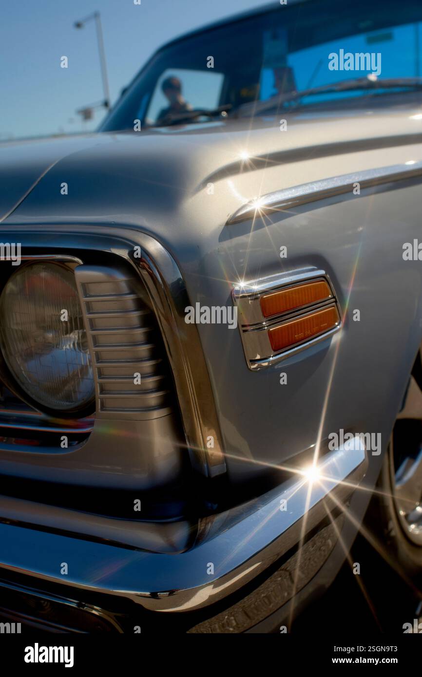 Close-up of a classic car's shiny chrome details under bright sunlight ...