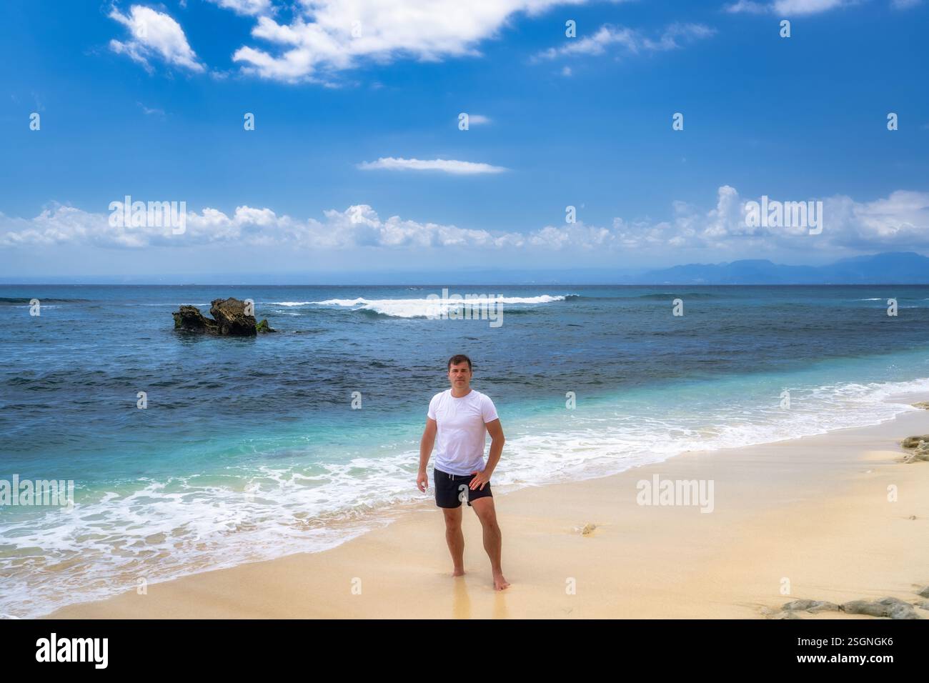 A man stands on a beautiful and picturesque beach, fully enjoying the ...