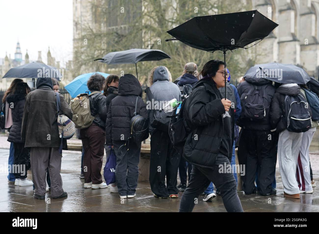 An umbrella is blown inside out by the wind as people shelter from the ...