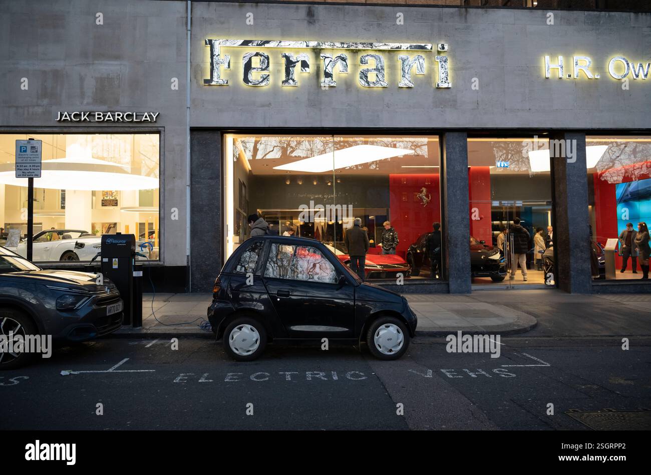 Two seater electric car being charged outside a Ferrari sports car ...