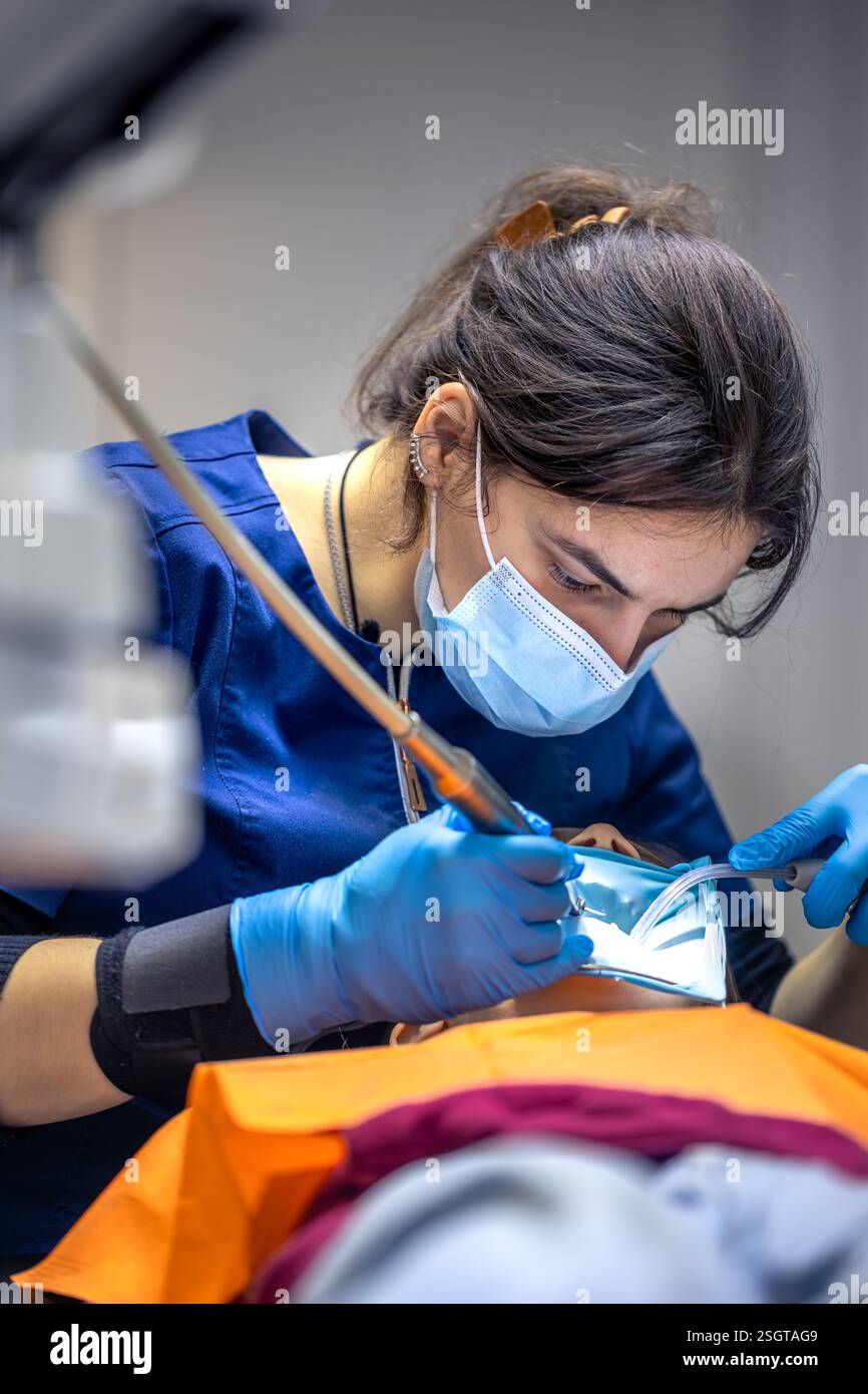 The dentist treats the child's tooth using a rubber dam. Close-up of ...