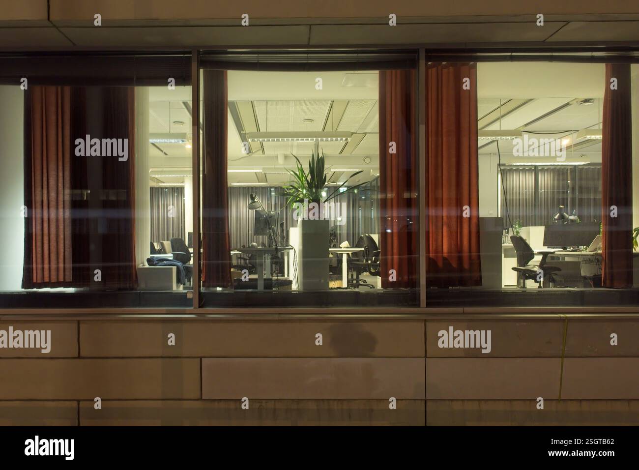 Modern office interior view from outside through window glass at night ...