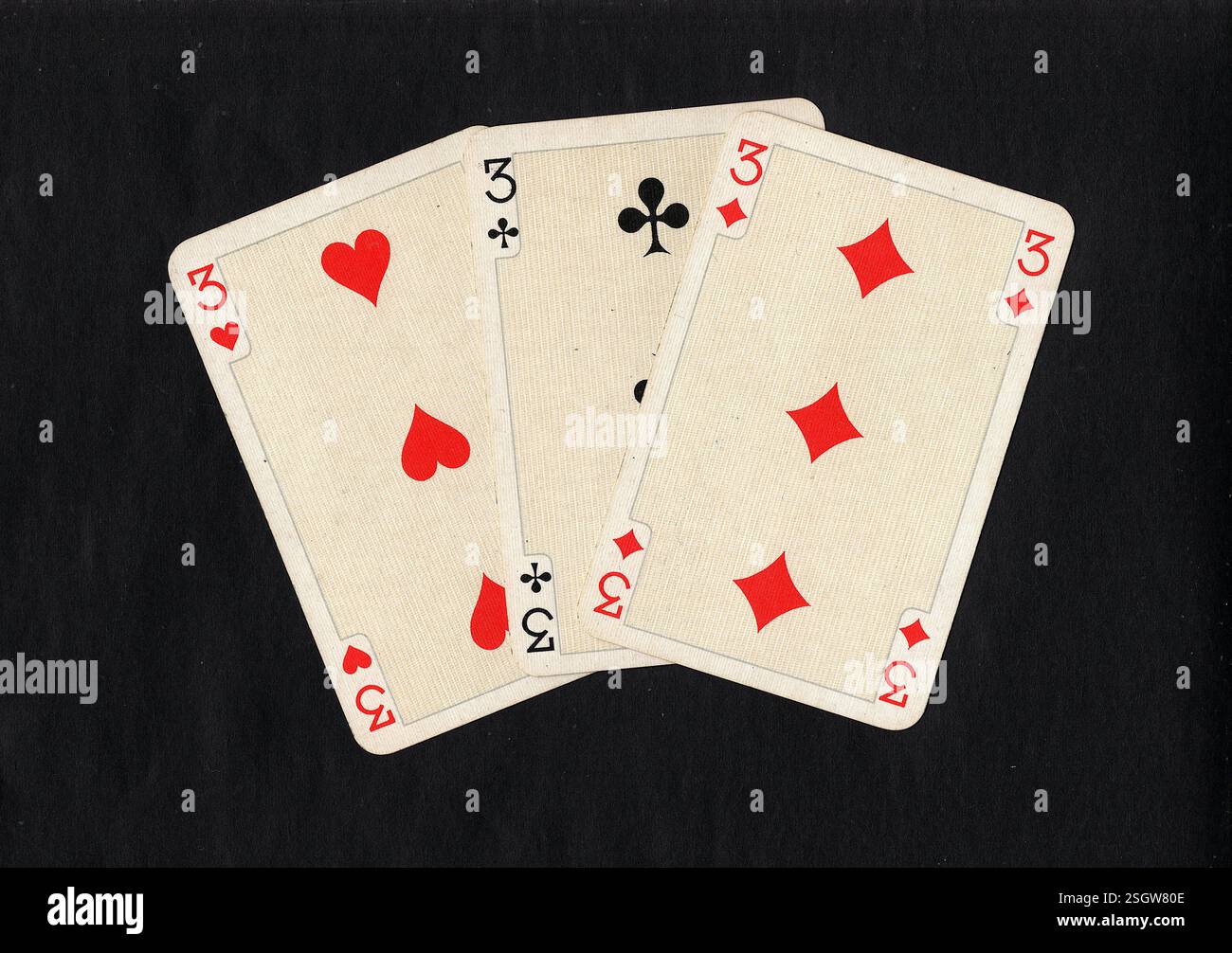 A hand of vintage playing cards showing three threes isolated on a ...