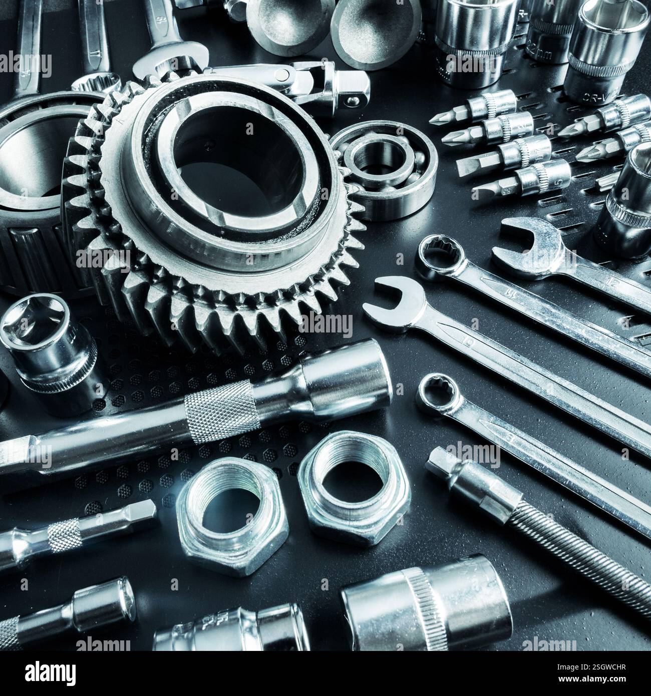 Collection of various metallic tools arranged neatly on a dark surface ...