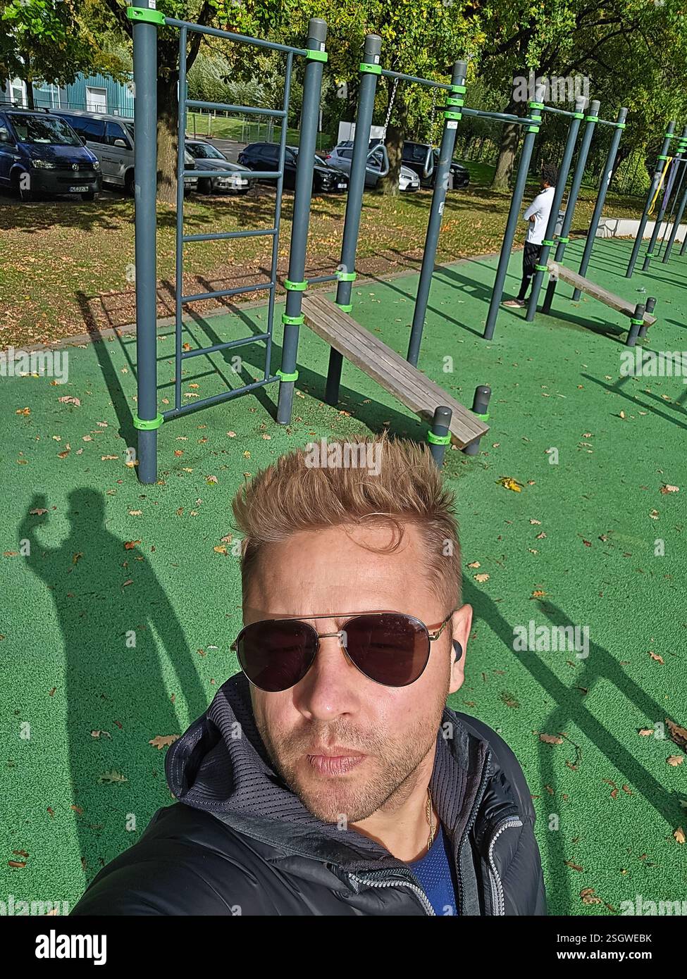 A man happily engages in outdoor fitness at a lively park, surrounded ...