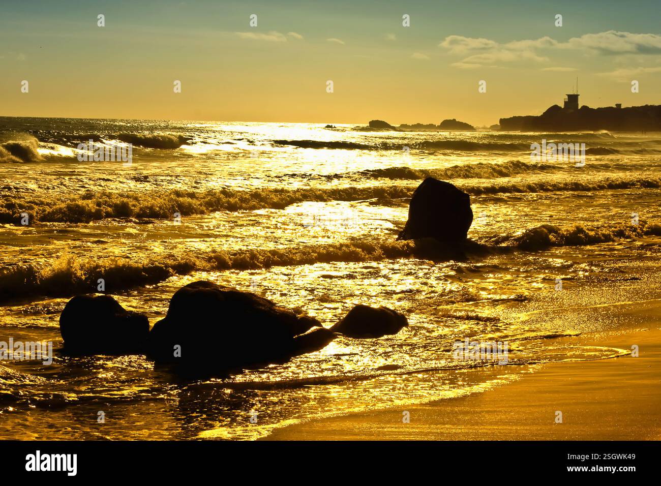 Beach with a large rock in the water. The rock is partially submerged ...