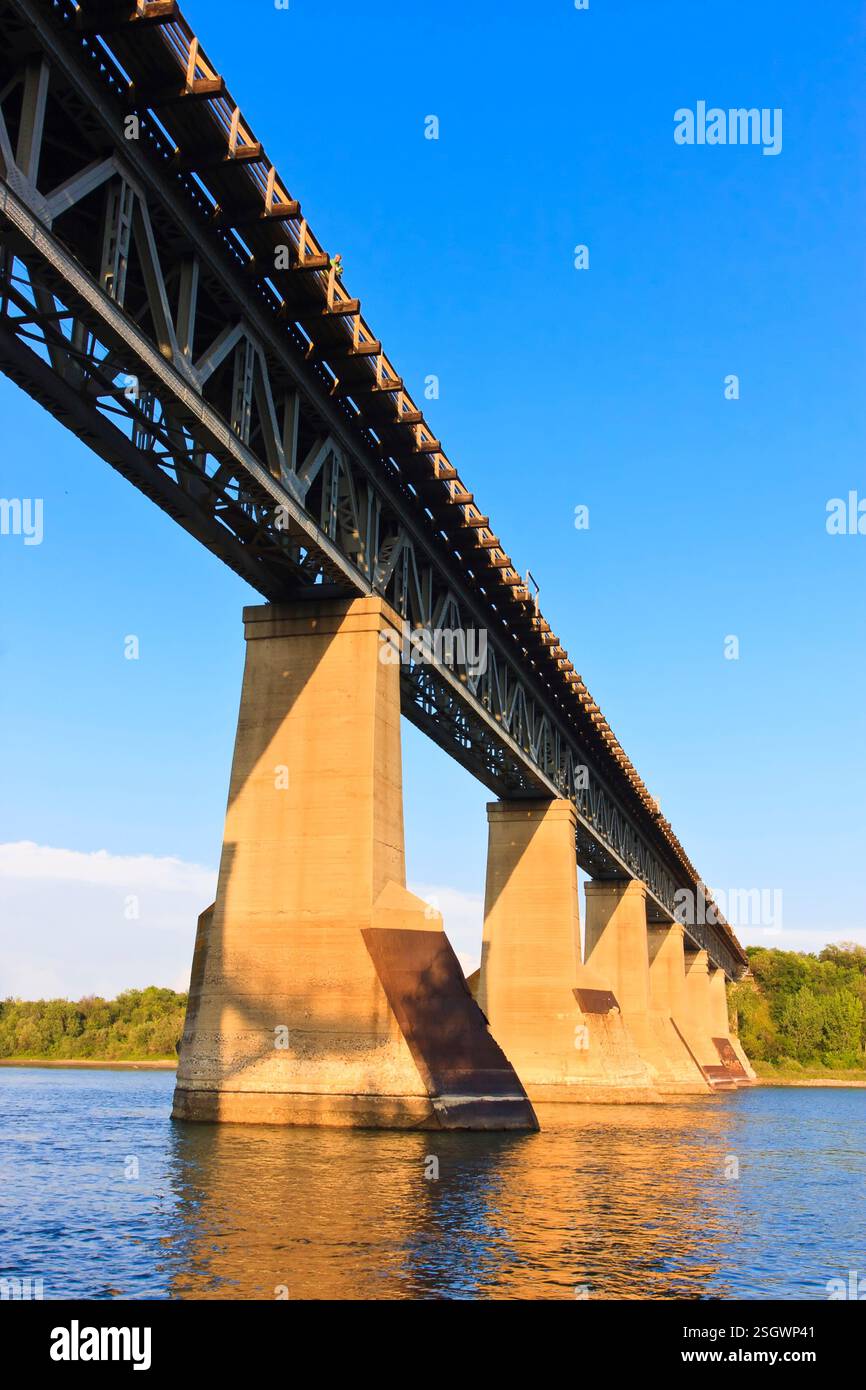 Bridge spans a river with a clear blue sky above. The bridge is made of ...