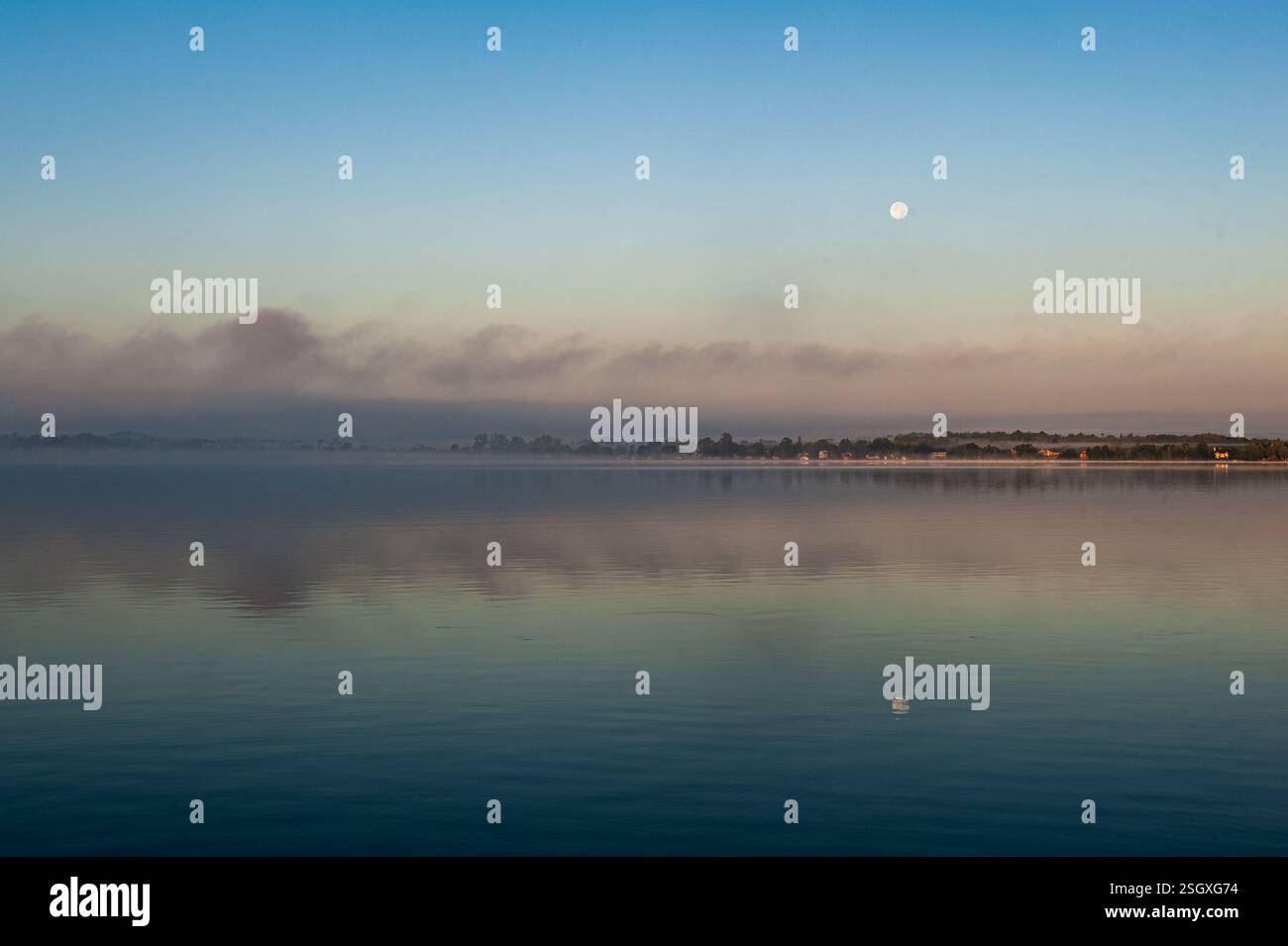 Full moon reflecting in the still water of Sturgeon Lake at sunset in ...
