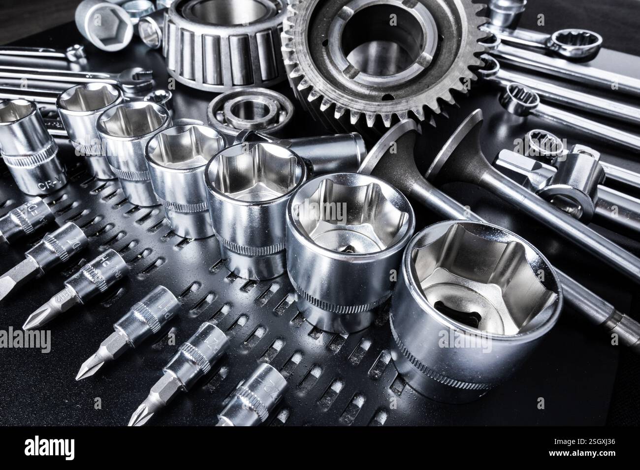 Collection of chrome tools arranged neatly on a black workbench in a ...
