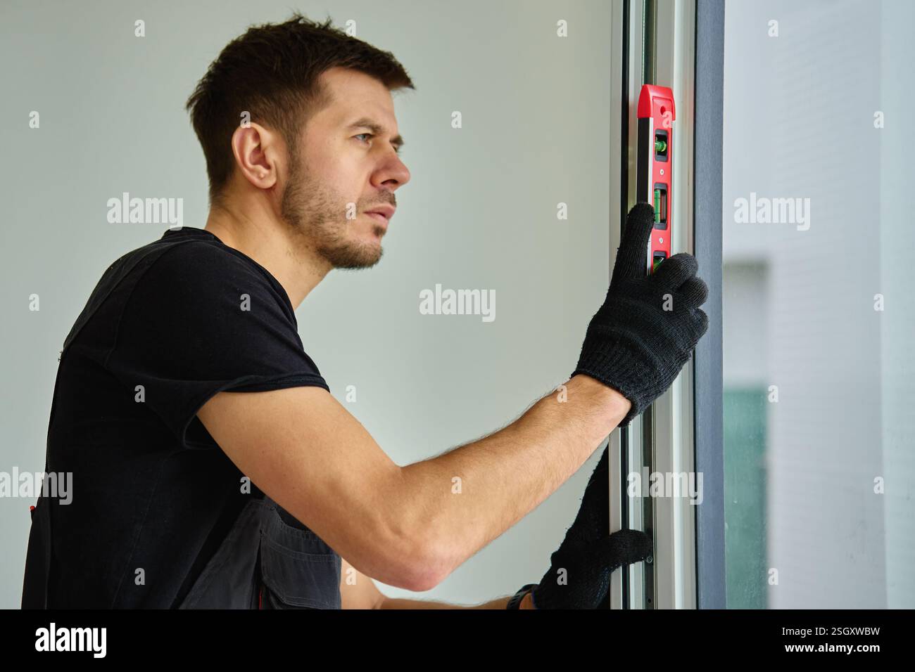 Professional builder using red spirit level for alignment of window ...