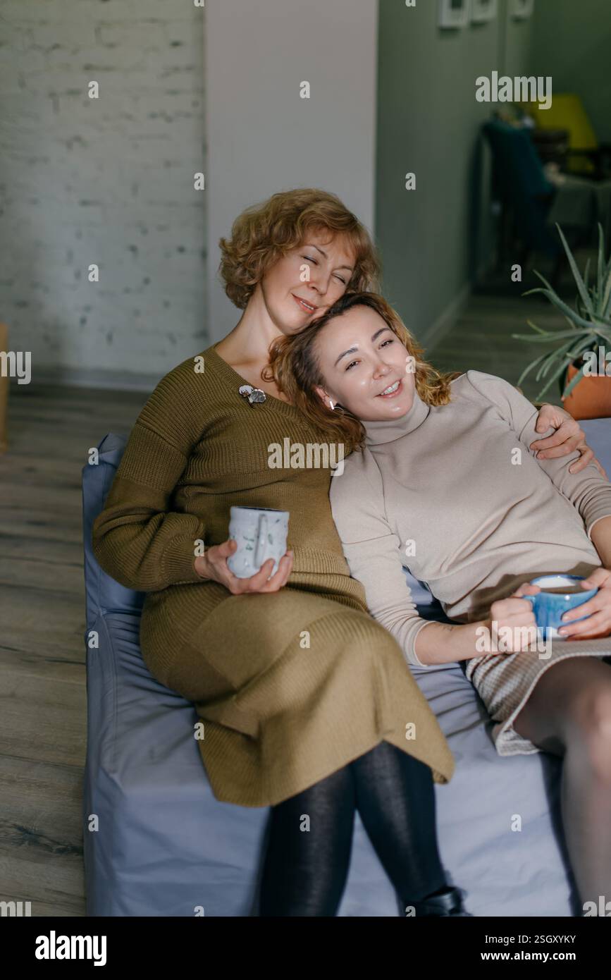 Elderly mother and young daughter bonding over tea, expressing ...