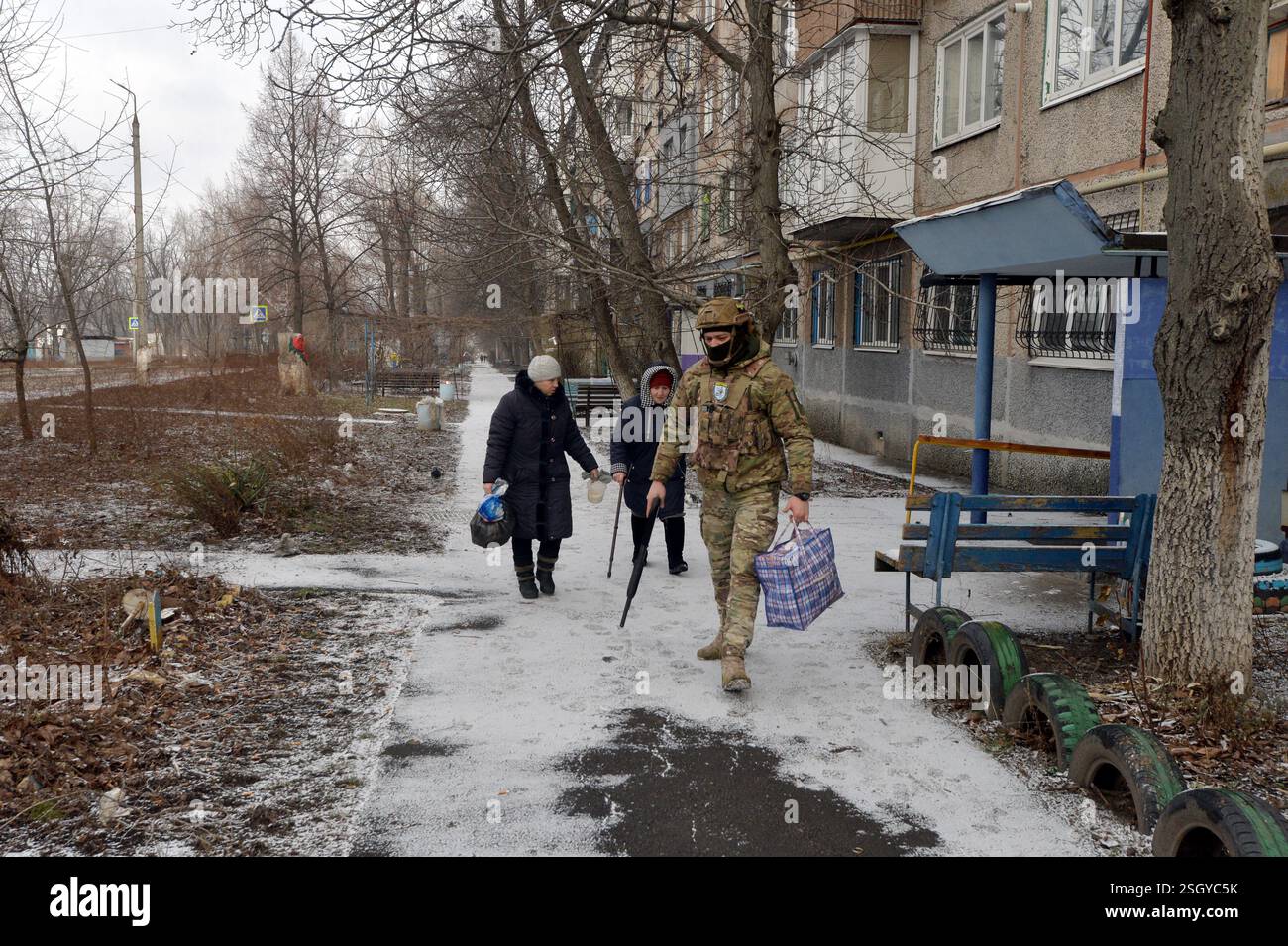 POKROVSK, UKRAINE - FEBRUARY 7, 2025 - A police officer helps two women ...