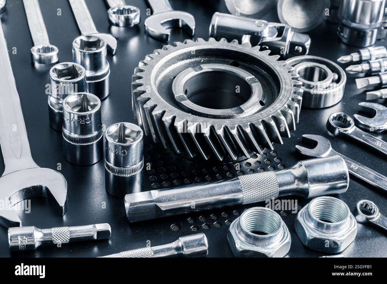 Collection of various metal tools and gears arranged on a workbench for ...