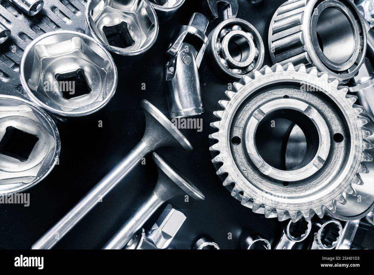Collection of metal tools and components arranged on a black background ...