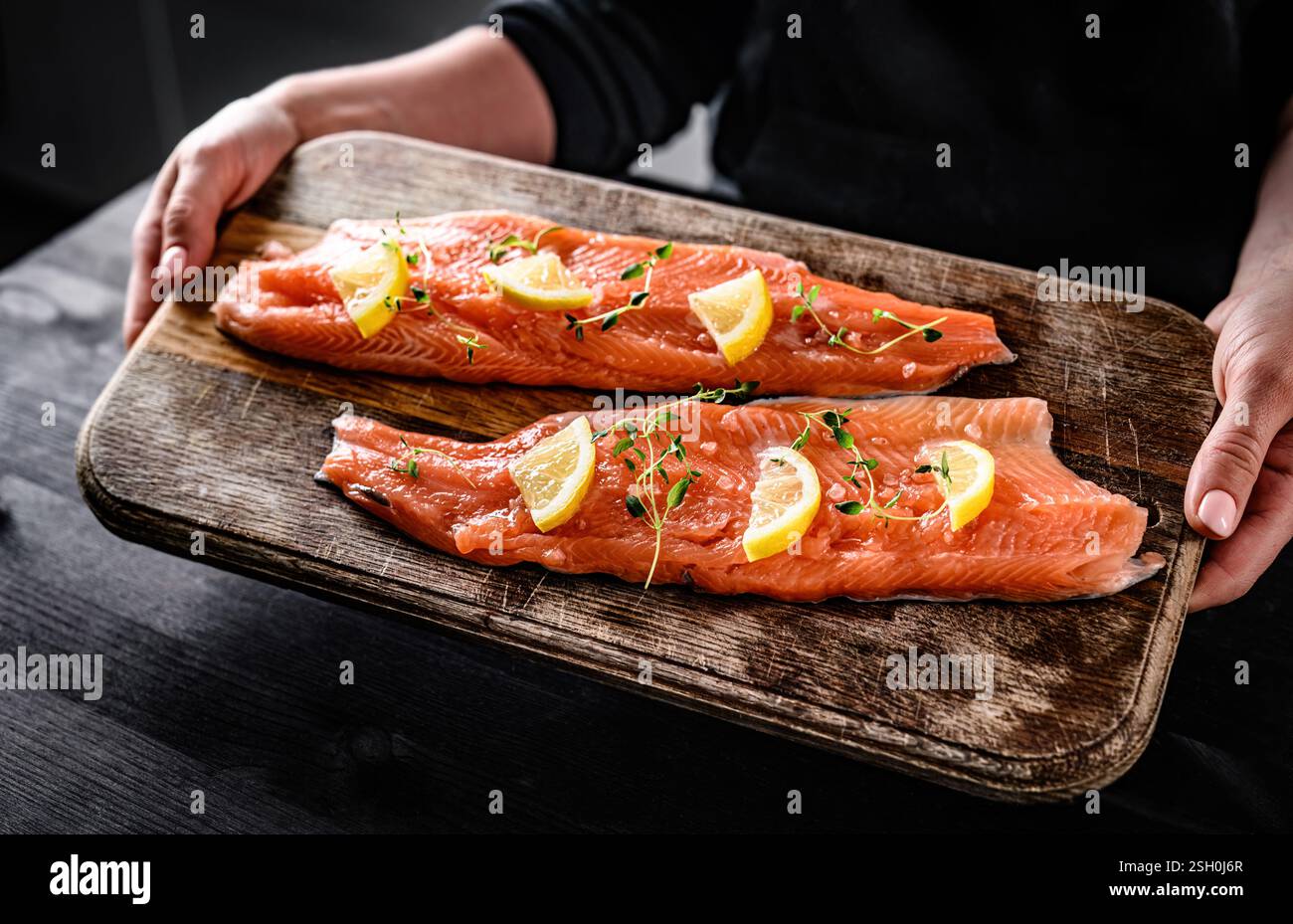 Girl hands holding fresh trout salmon filet with herbs and lemons ...