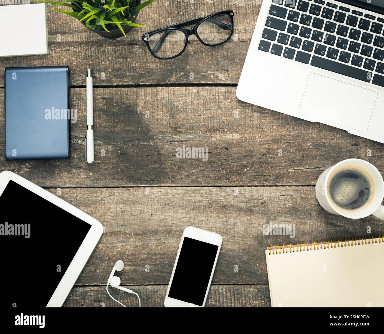 Desk workspace setup with technology including laptop, tablet, and ...