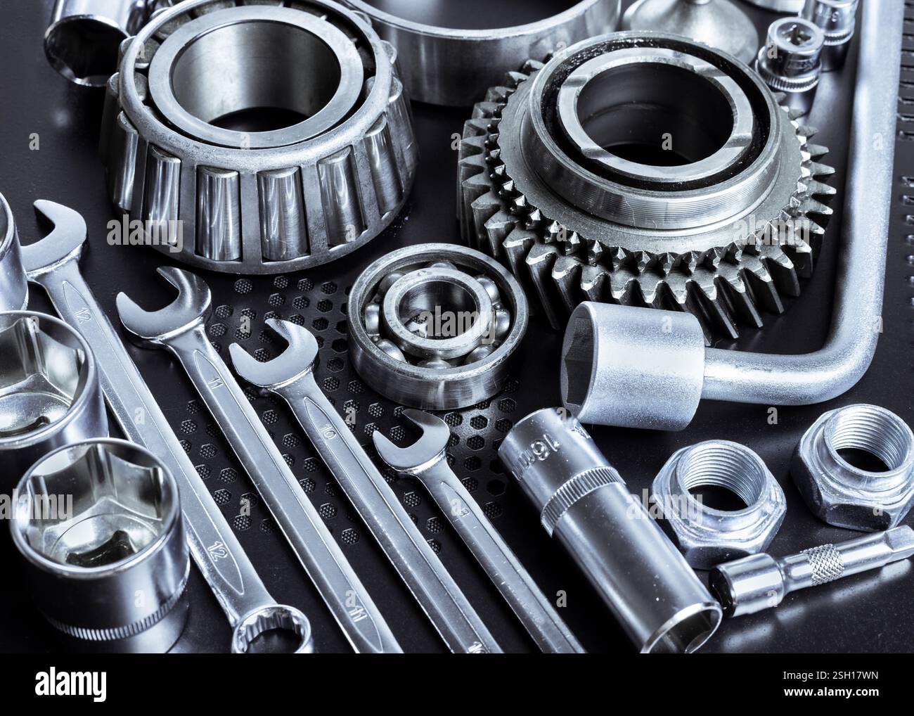 Collection of silver tools and mechanical parts arranged on a dark work ...