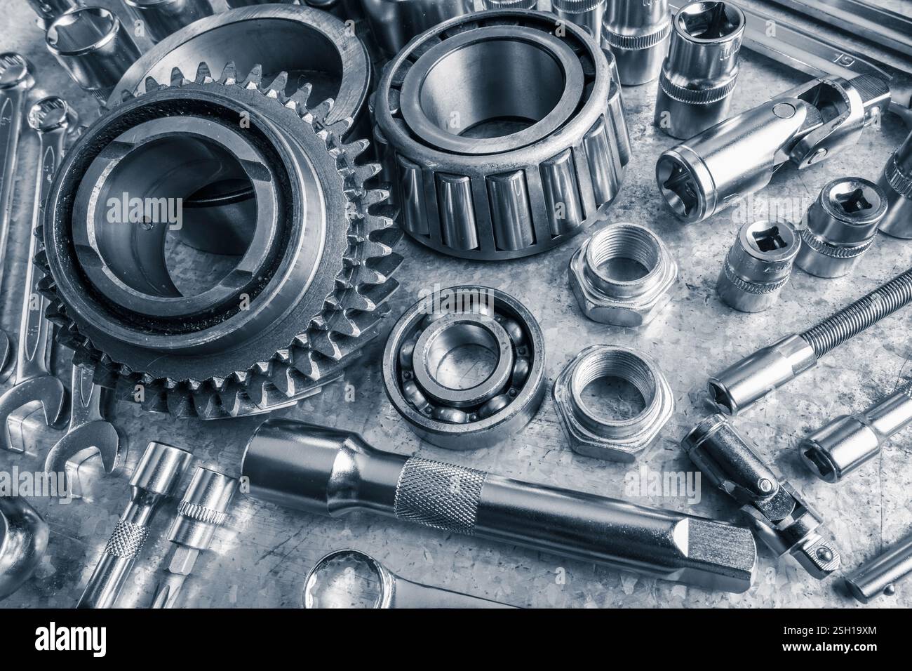 Collection of metallic tools and components arranged on a workbench in ...