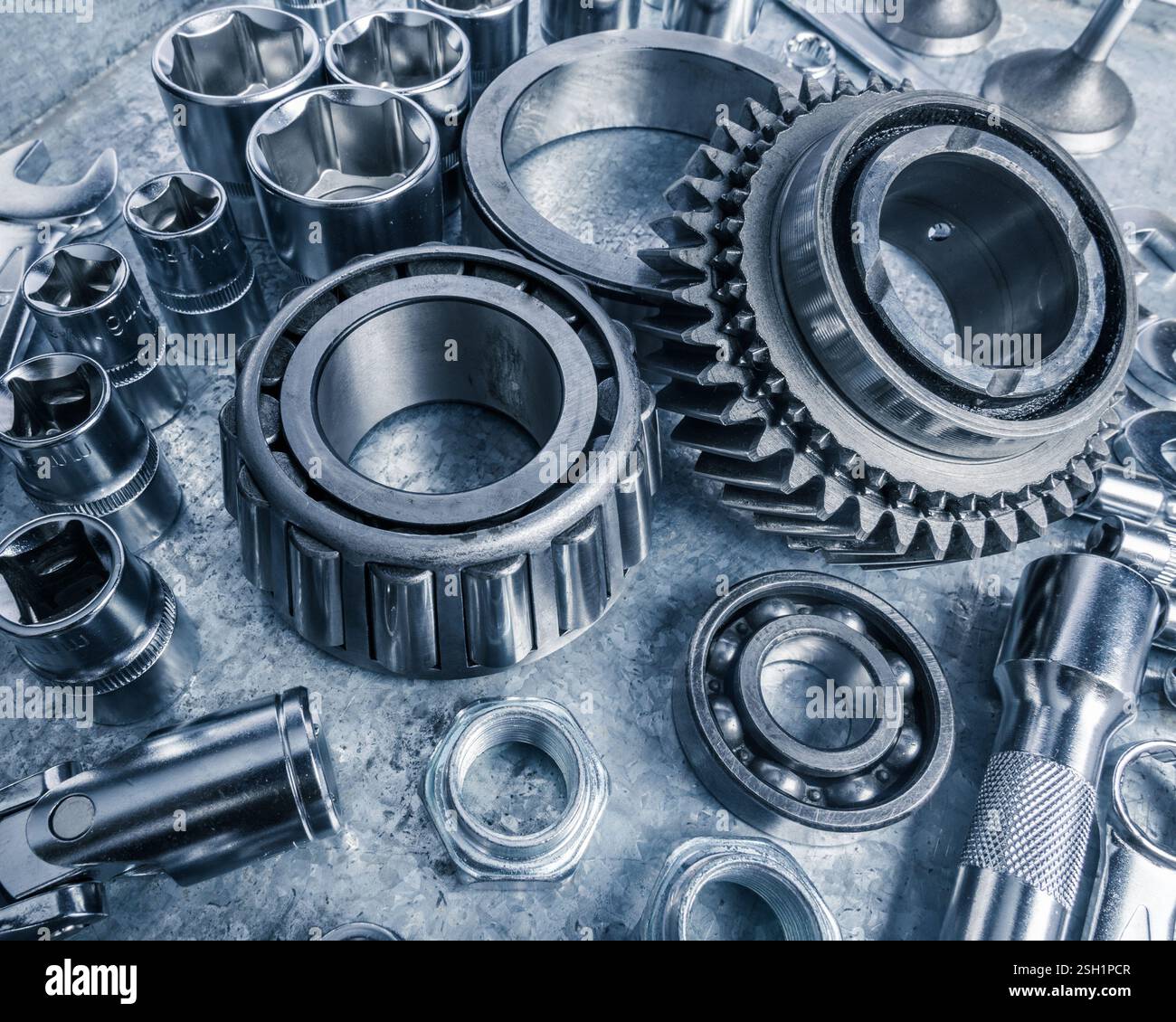 Collection of various mechanical parts and tools on a workbench in a ...