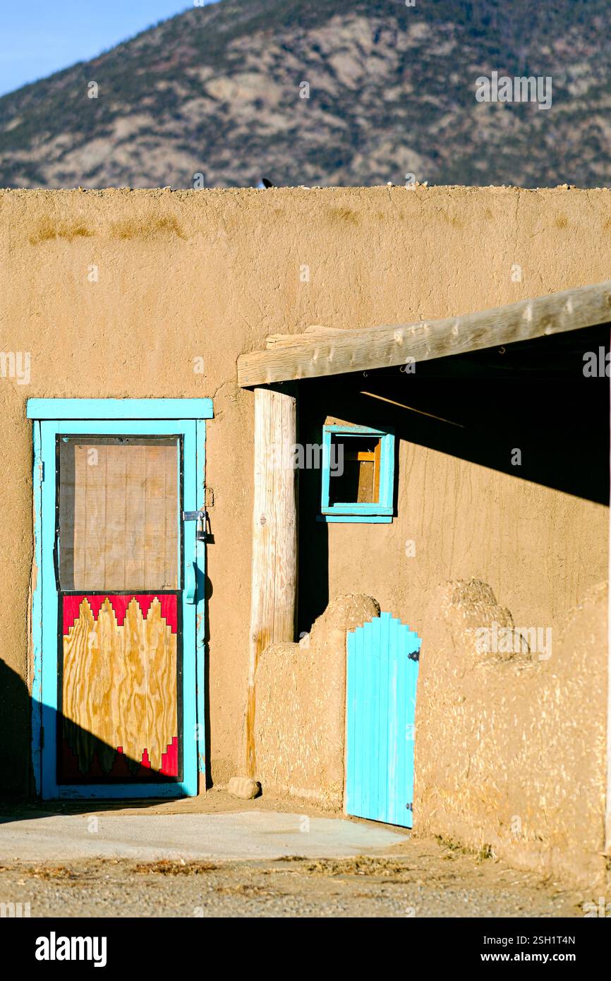Traditional Adobe Building with Turquoise Doors and Mountain Backdrop ...