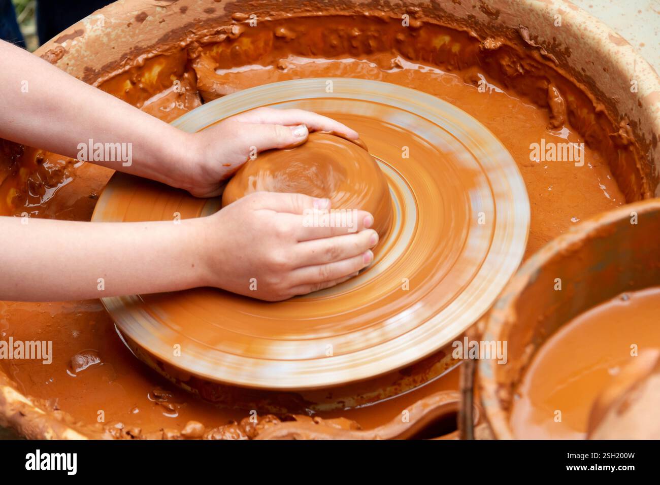 Pottery training. Rotating a clay pot on a machine. Hands knead clay ...