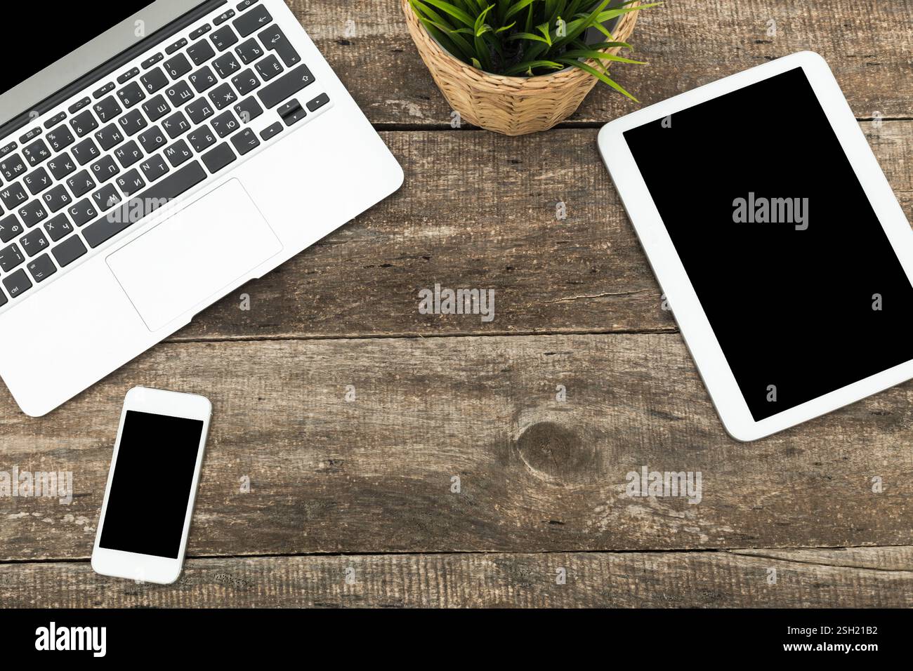 Workspace setup with laptop, tablet, and smartphone on wooden desk ...
