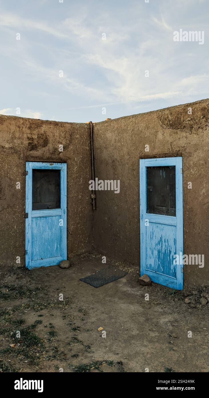 Rustic Adobe Home with Vibrant Blue Door and Shadows Stock Photo - Alamy