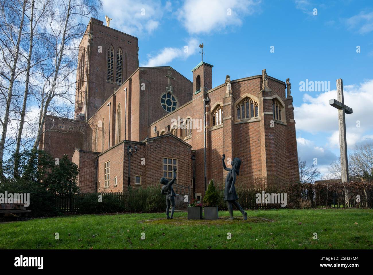 Rear view of Guildford Cathedral with a large wooden cross and statues ...
