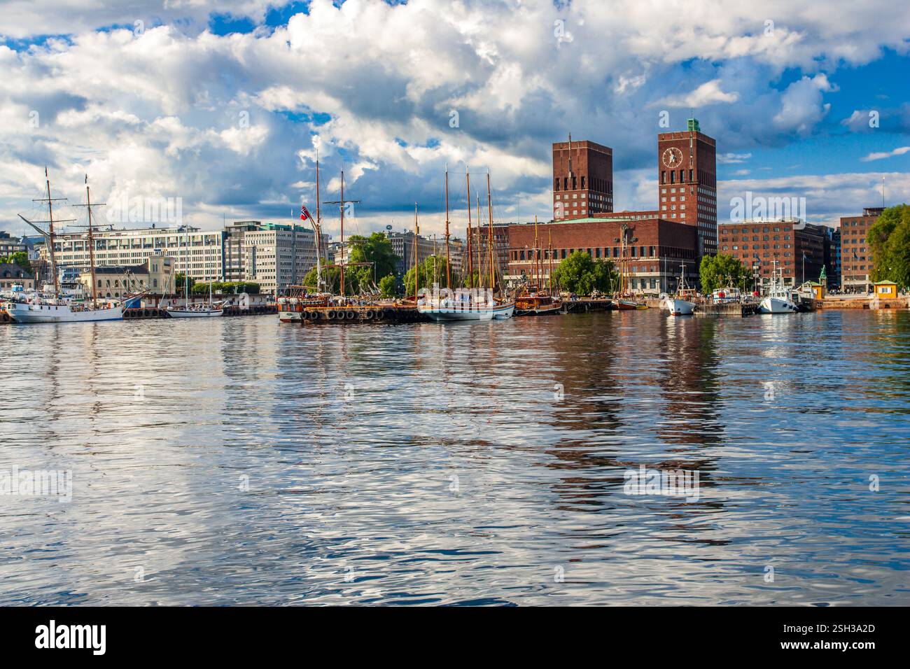 Clear blue skies reflect on the Fjord as Oslo City Hall stands proudly ...