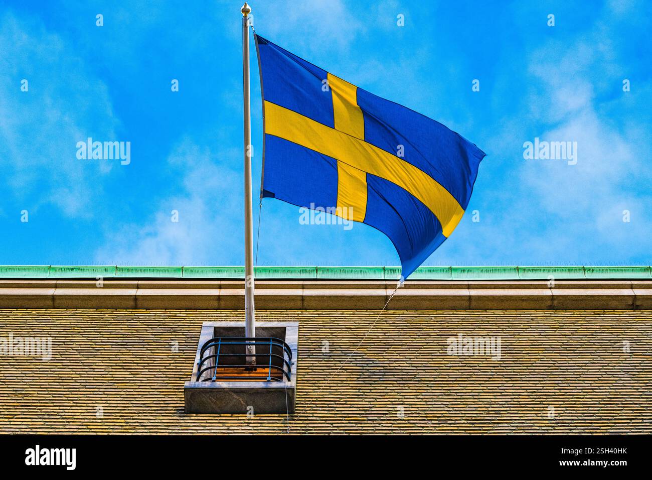 The Swedish flag waves against a bright blue sky from a building in ...