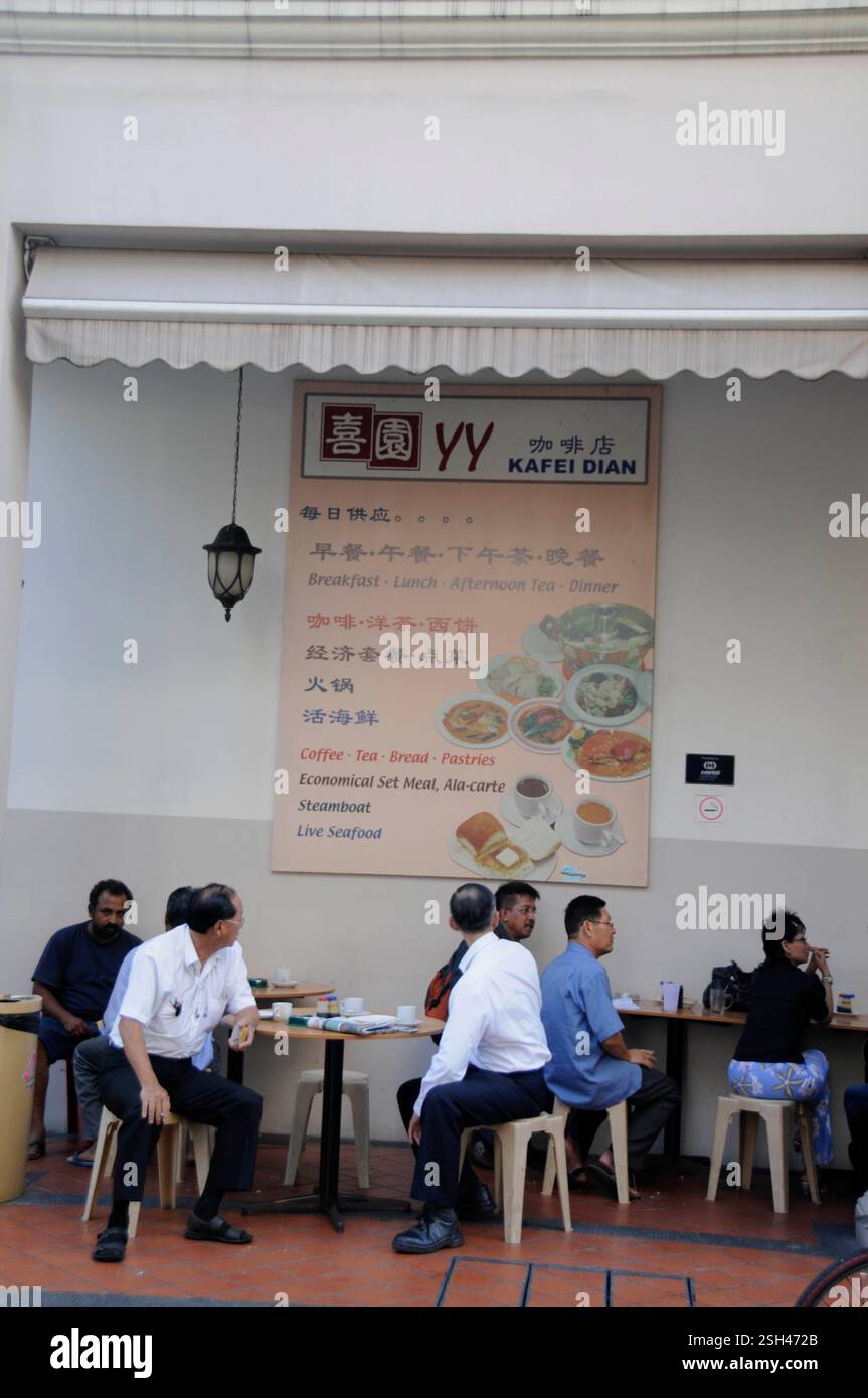 A group of Chinese men study the on-the-wall menu at an open restaurant ...
