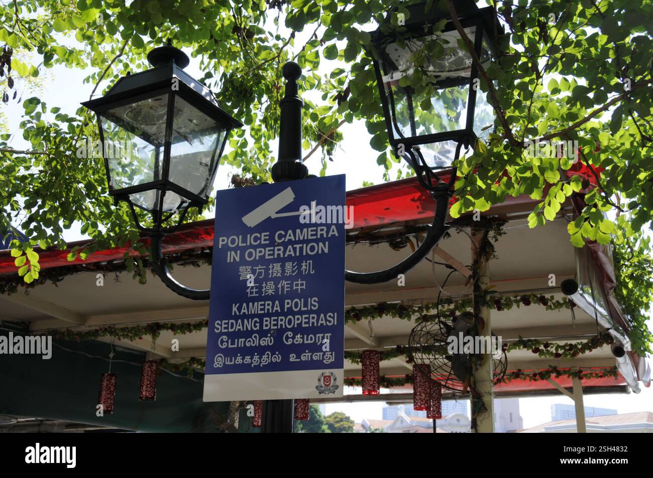 A Singapore Police camera sign attached to an ornamental street lamp in ...