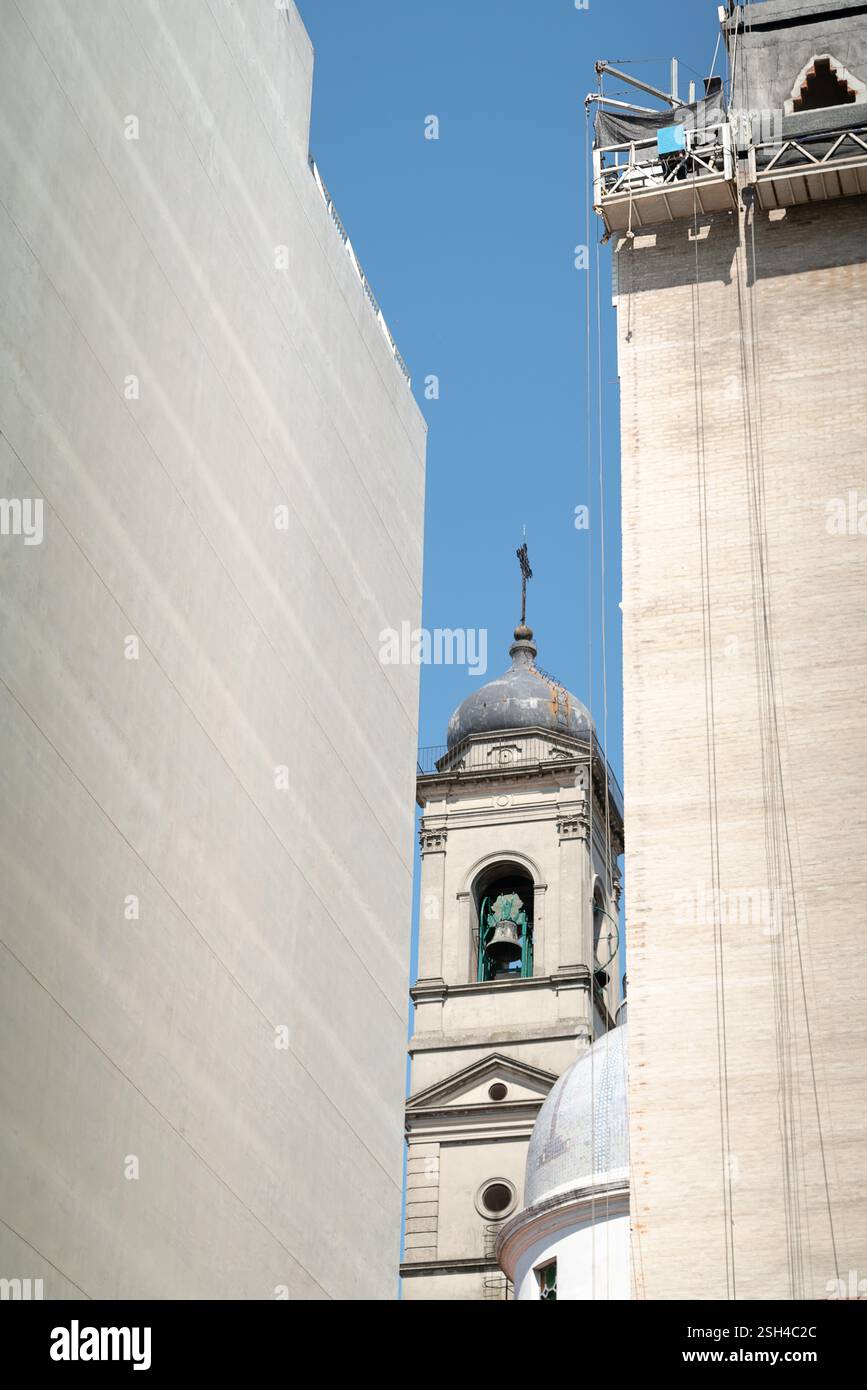 A church dome with bell tower between two large walls of new buildings ...
