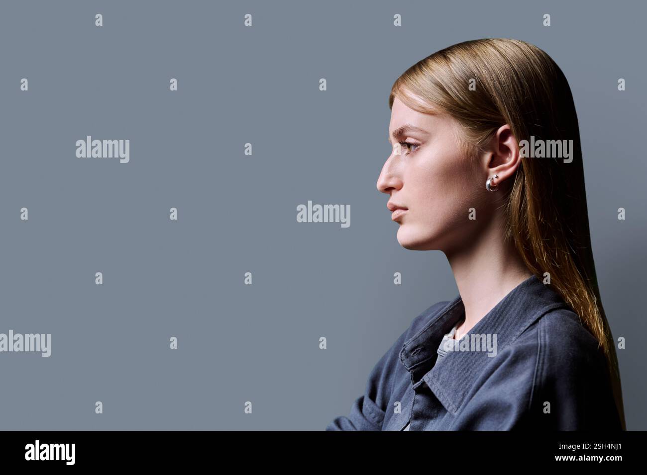 Profile view, young serious female looking forward on gray studio ...