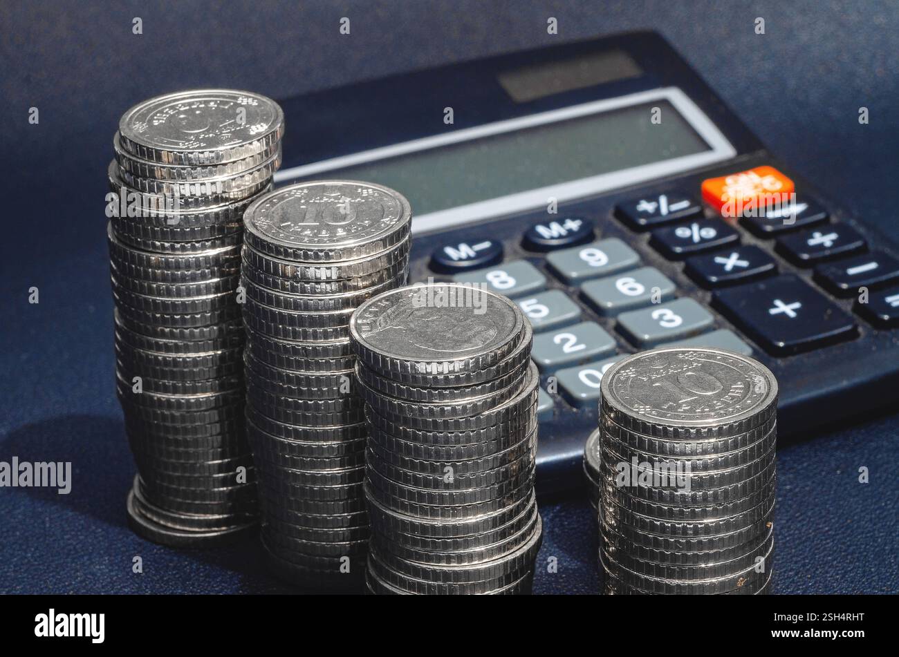 Columns of coins next to calculator. Blurred background. Debt ...