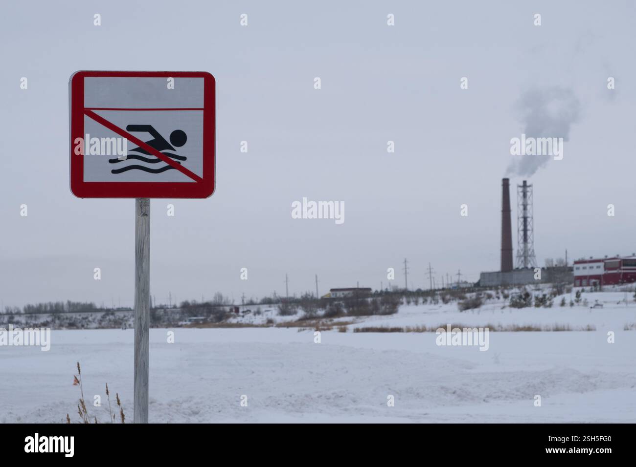 Warning sign on edge frozen lake with factory in background Stock Photo ...