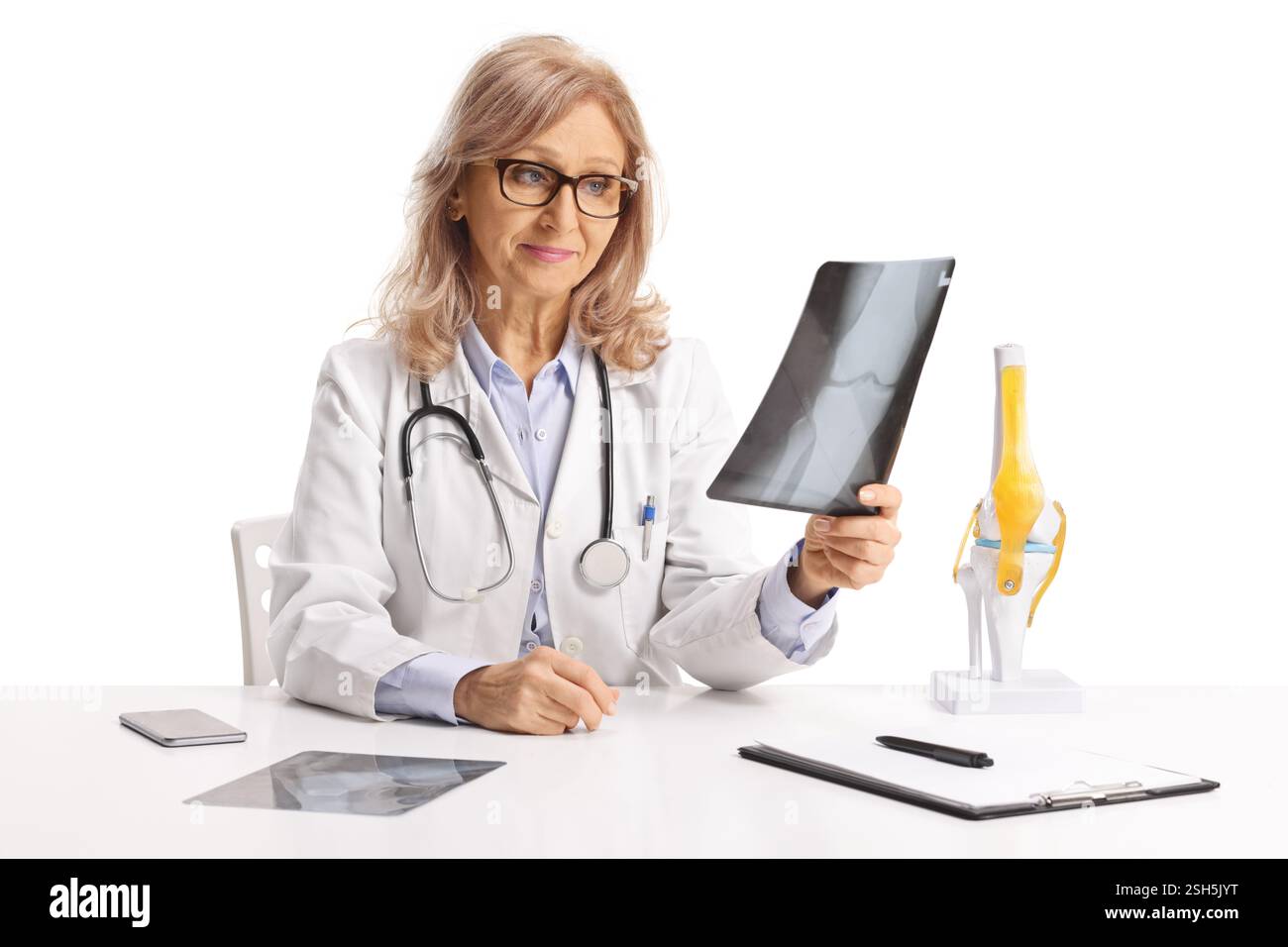 Female doctor sitting behind a desk and checking an x-ray image ...